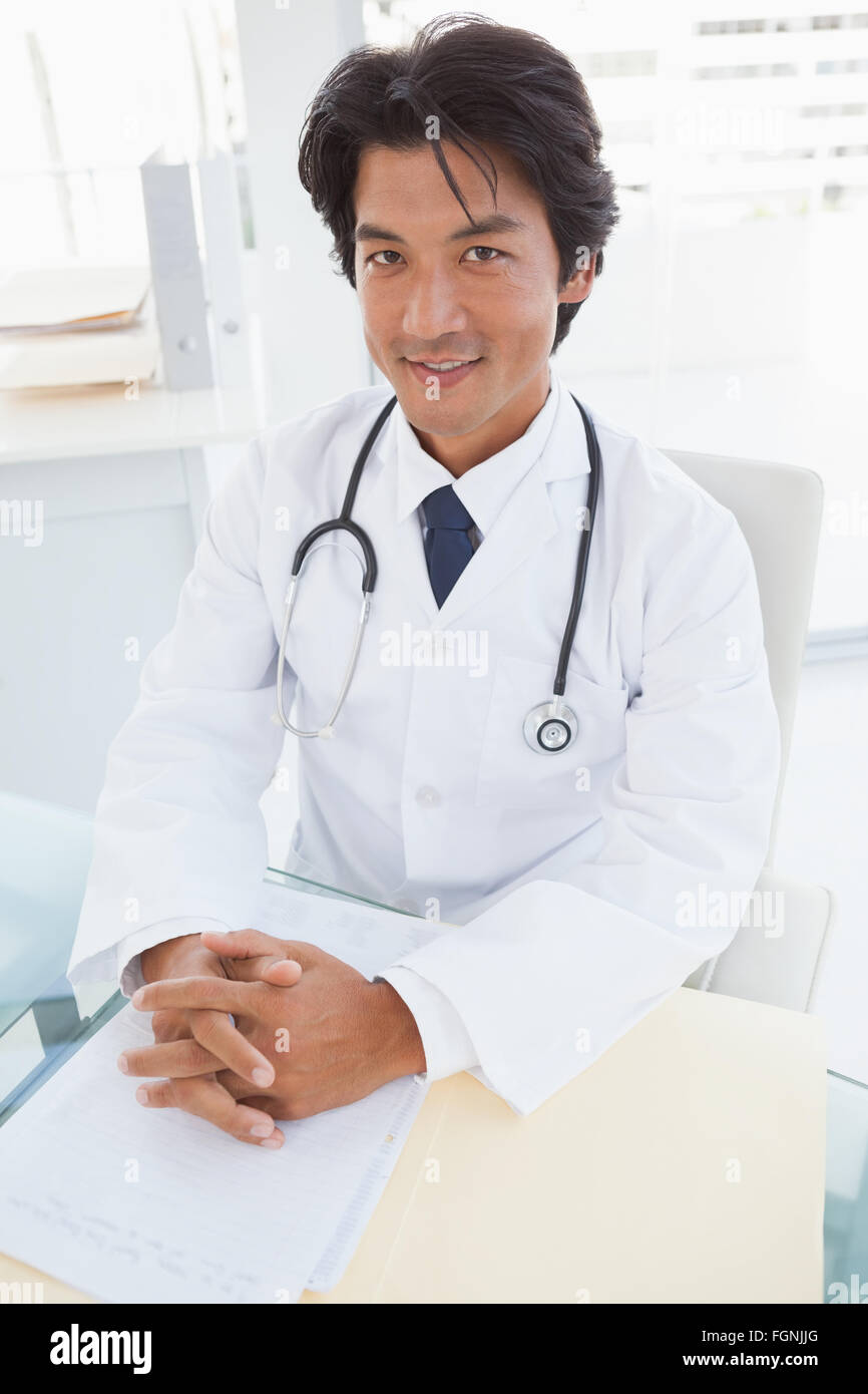 Smiling doctor sitting at his desk Stock Photo - Alamy