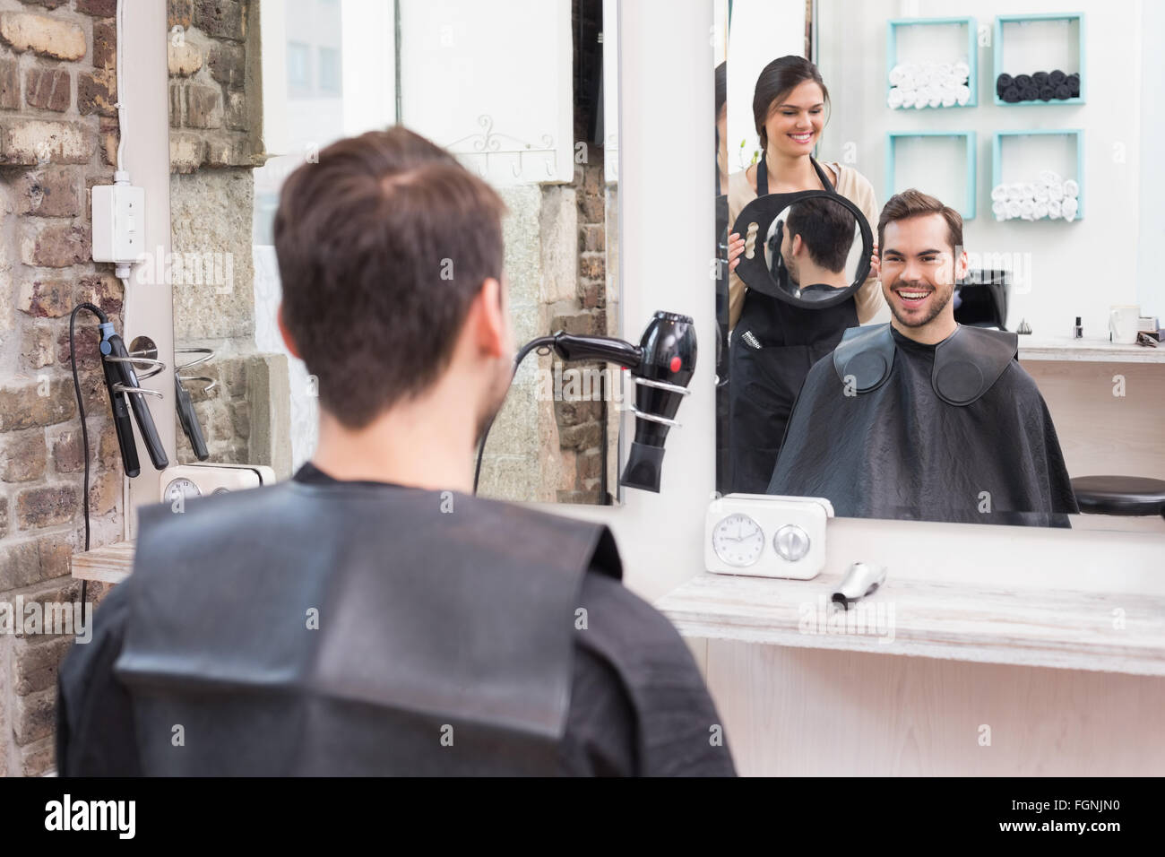 Pretty hair stylist showing man new haircut Stock Photo - Alamy