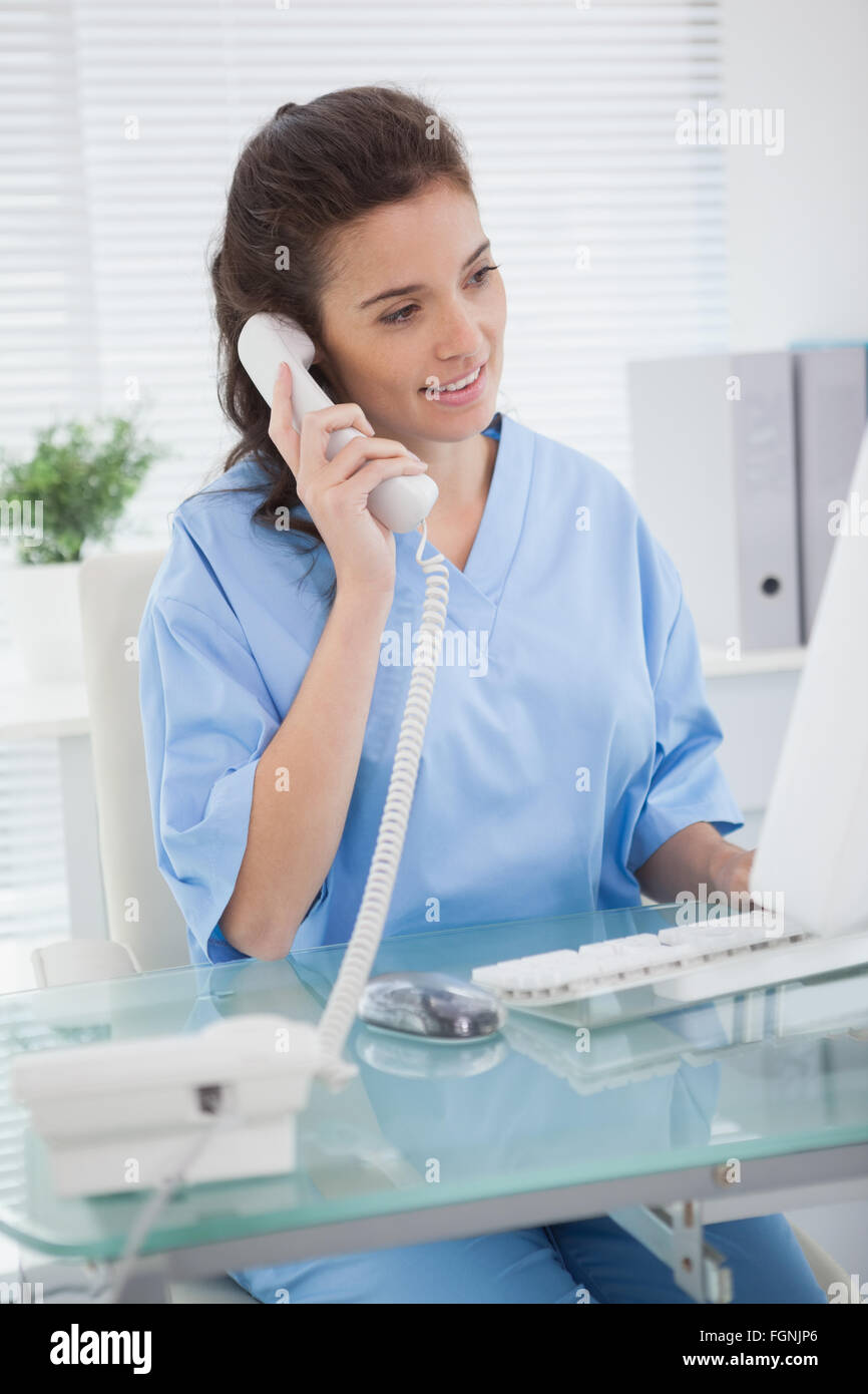 Smiling doctor phoning and using computer Stock Photo - Alamy