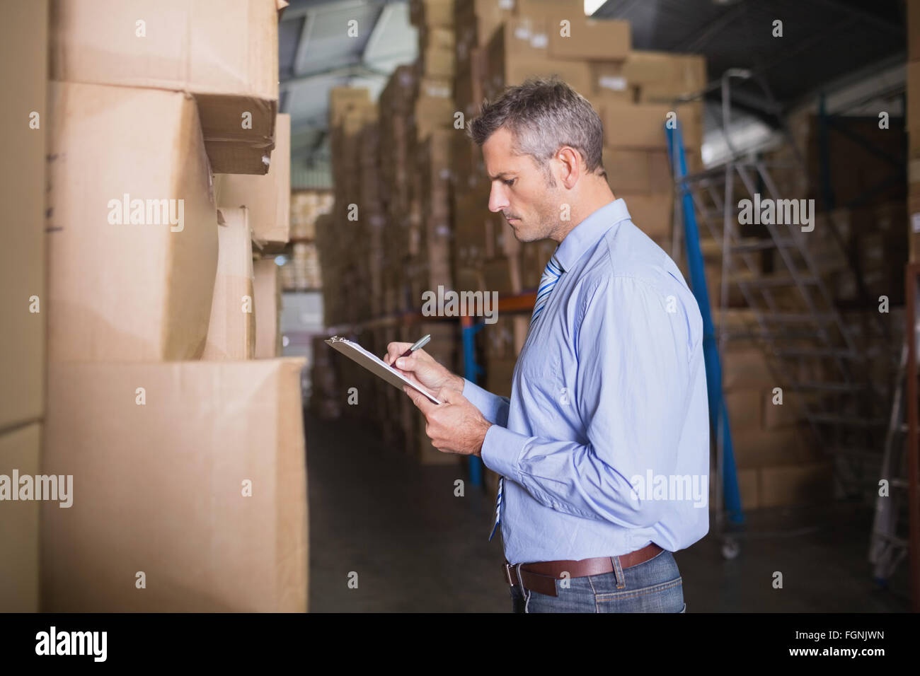 Manager holding clipboard in warehouse Stock Photo - Alamy