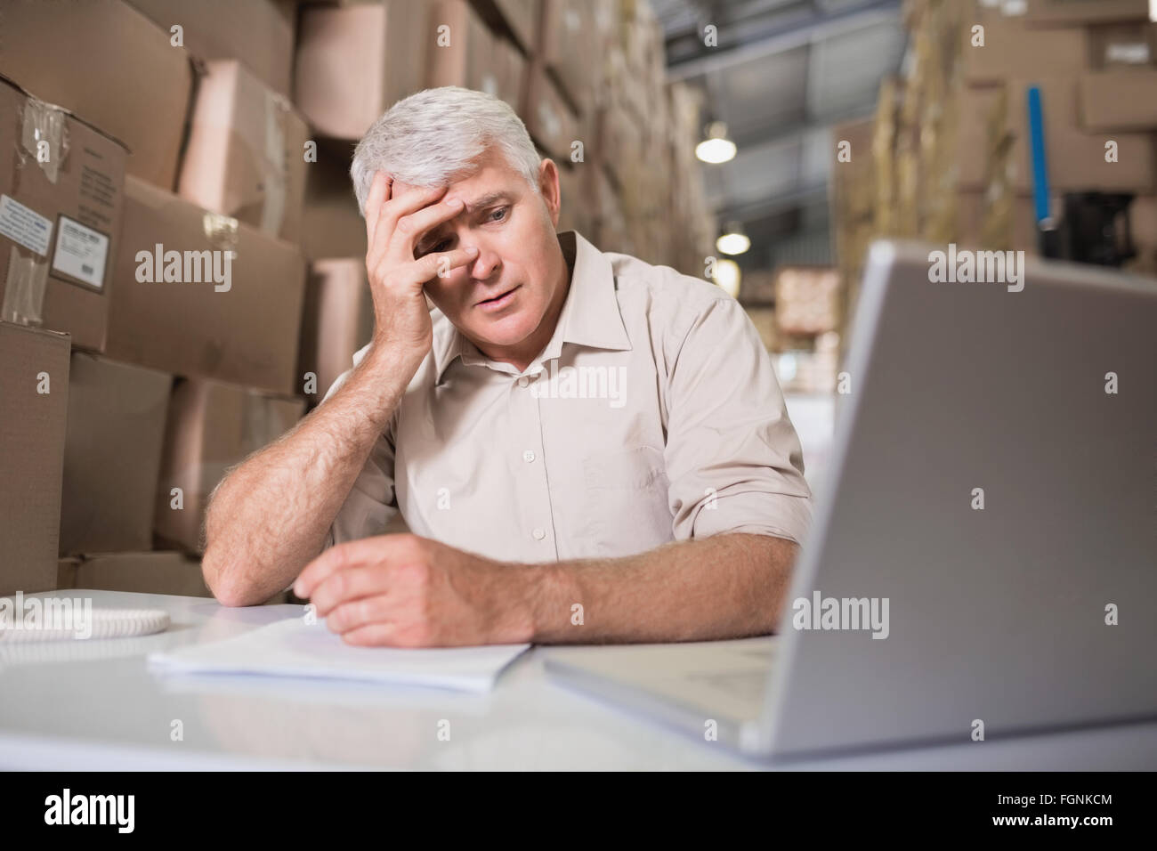 Worried warehouse manager with laptop Stock Photo - Alamy