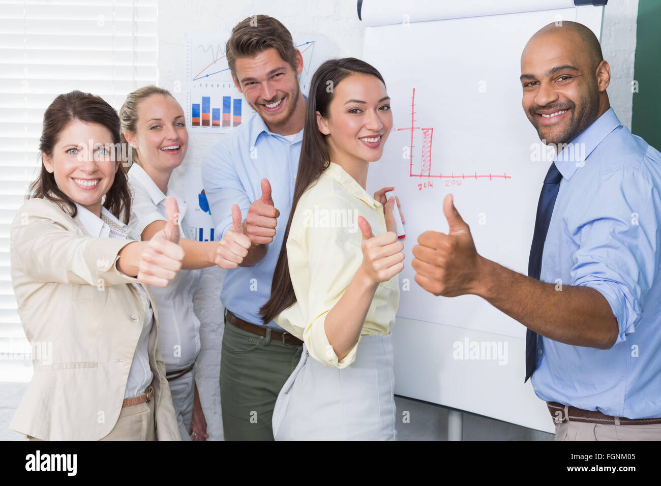 Smiling business team gesturing thumbs up in meeting Stock Photo - Alamy
