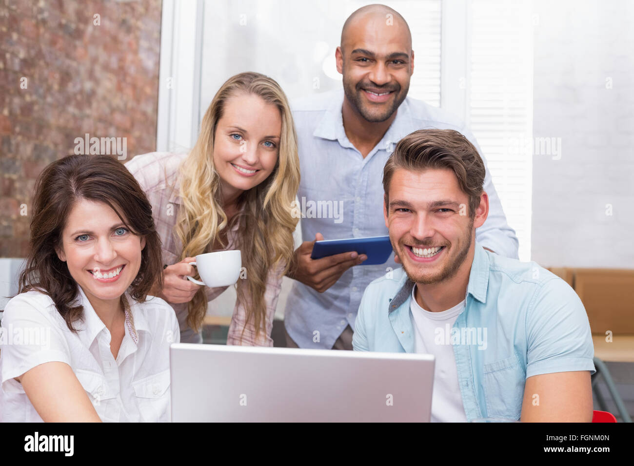 Business people looking at camera behind a laptop Stock Photo - Alamy