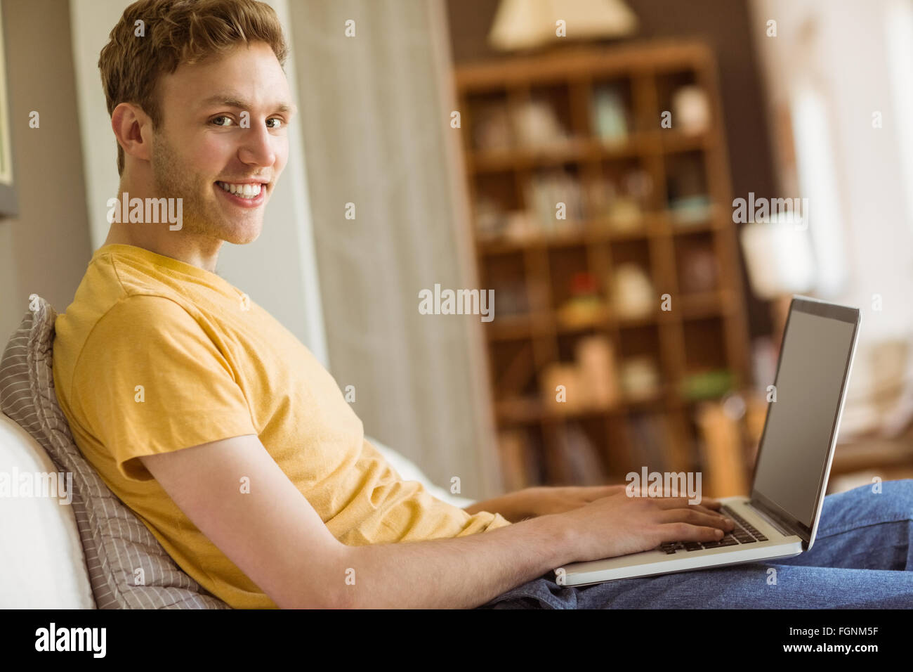 Young man using laptop on his couch Stock Photo - Alamy