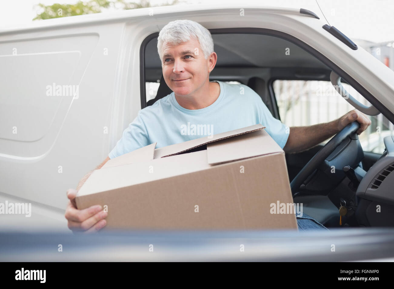 Man with carton box in front of van Stock Photo - Alamy
