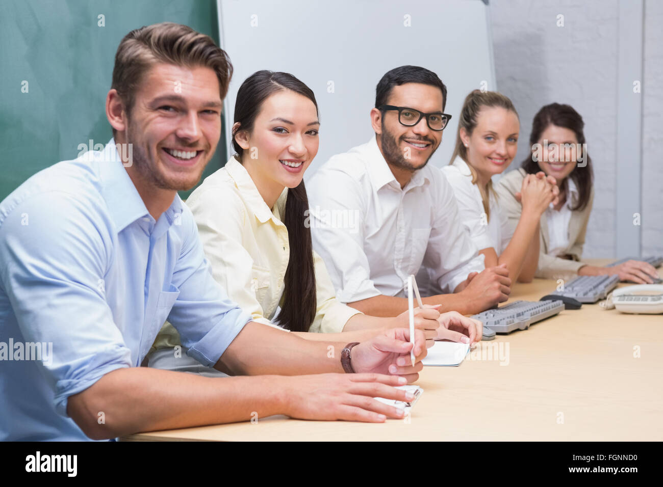 Smiling business team sitting in a line Stock Photo - Alamy