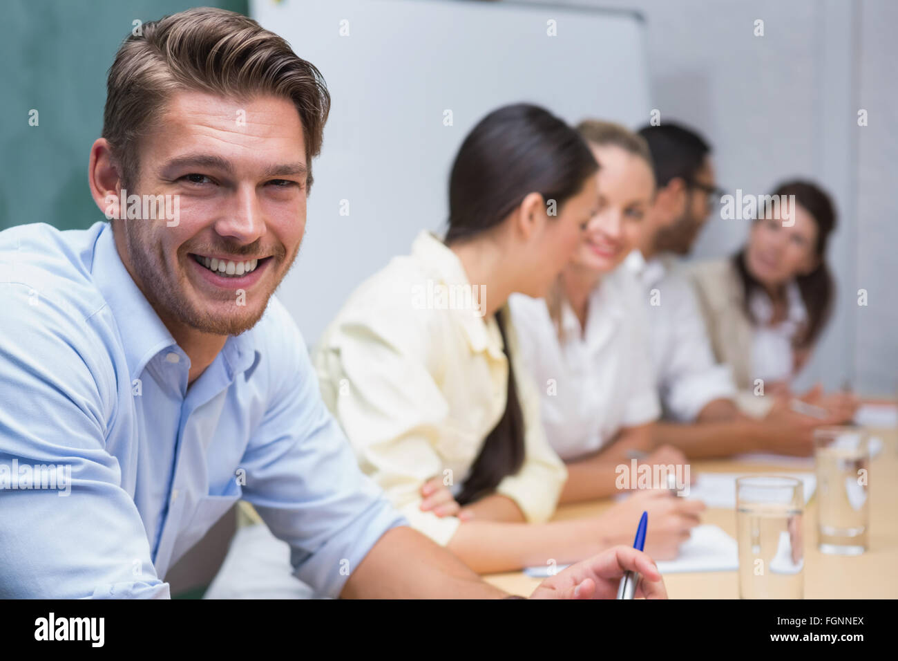 Business man smiling at camera with team behind him Stock Photo - Alamy