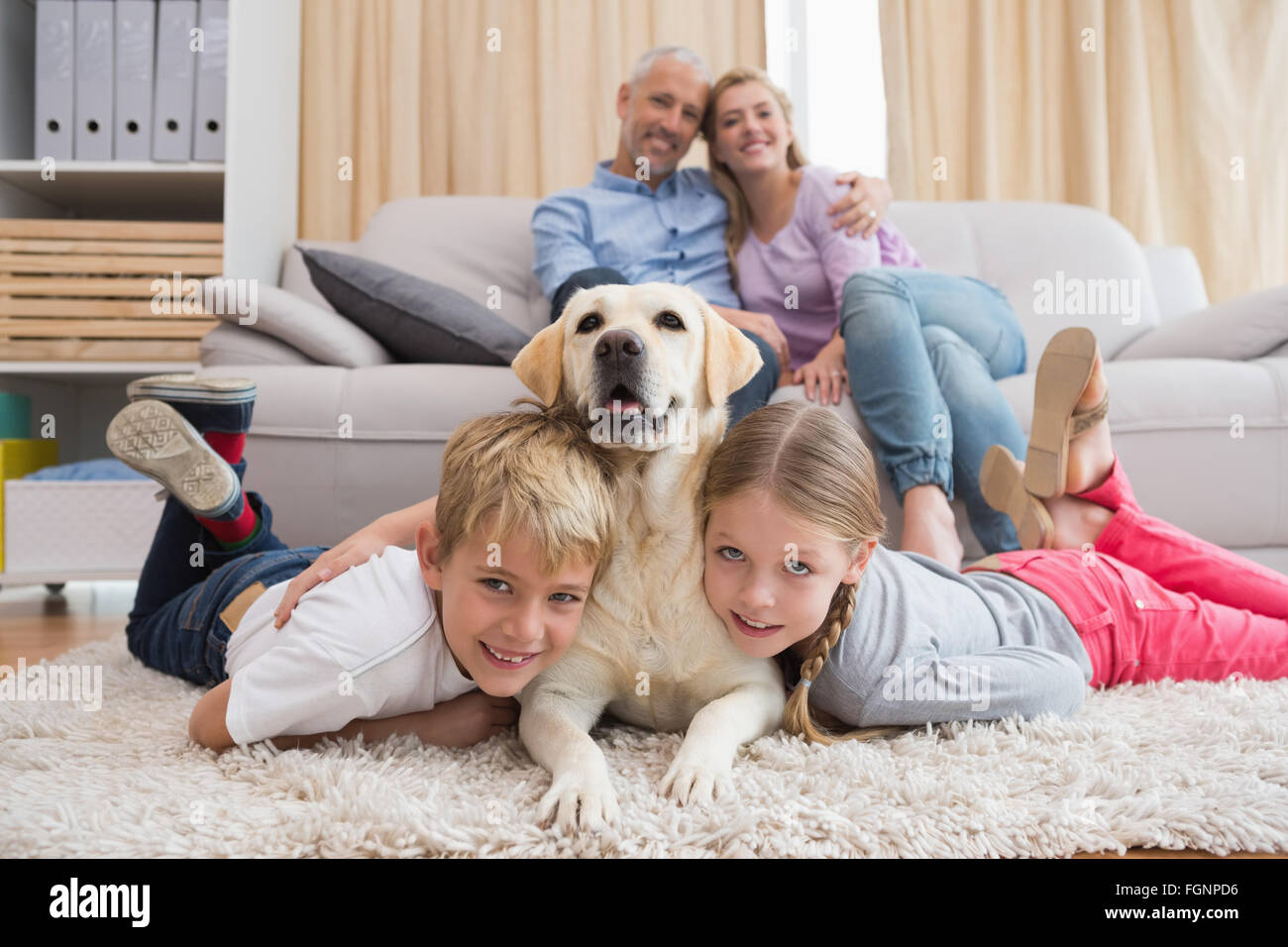 Parents watching children on rug with labrador Stock Photo - Alamy