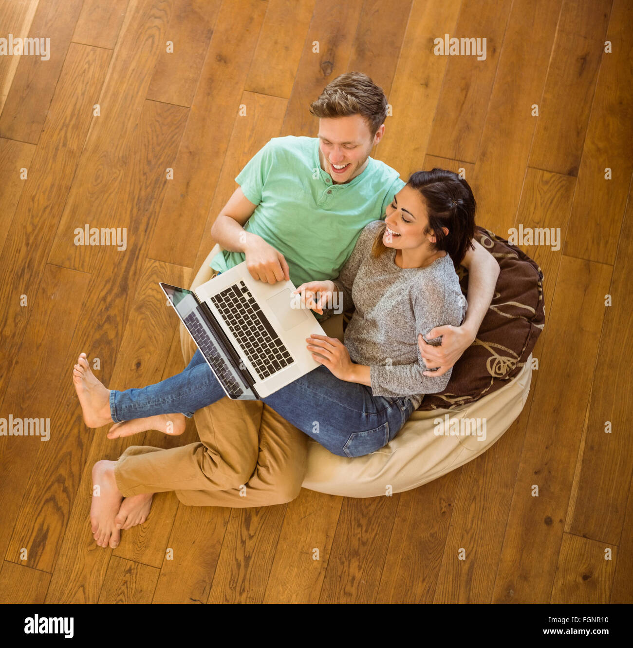 Cute couple using laptop on beanbag Stock Photo - Alamy