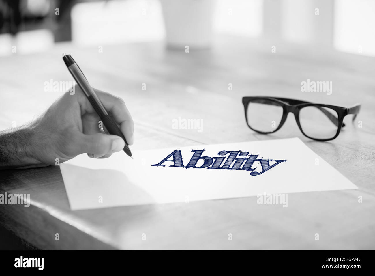 Ability against side view of hand writing on white page on working desk ...