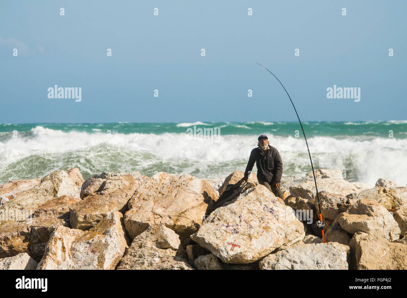 Fisherman Angler, during rough sea, alone angling on a mediterranean ...