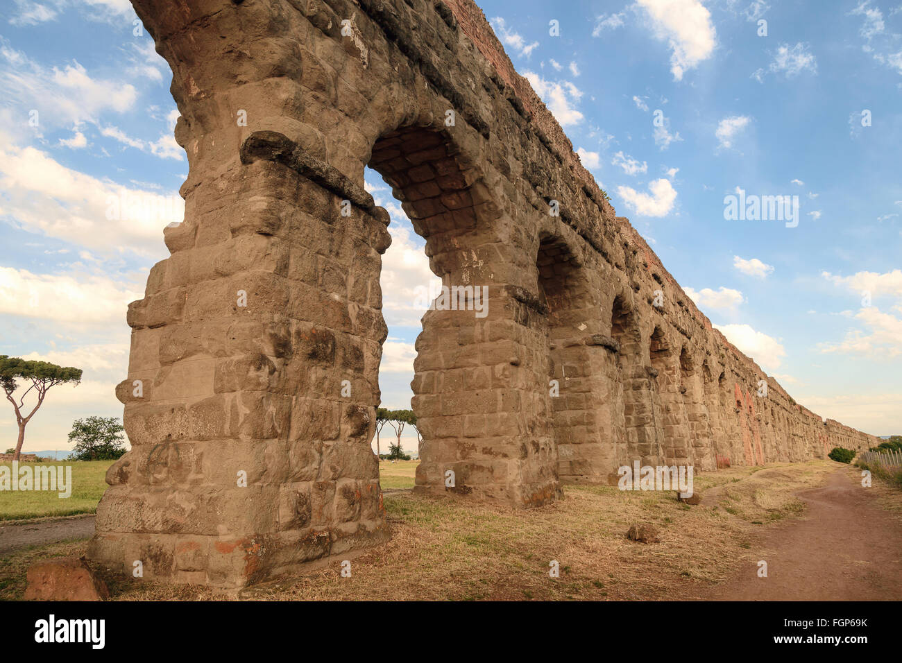 Arches of an ancient Roman aqueduct, made of blocks of tufa. A path ...
