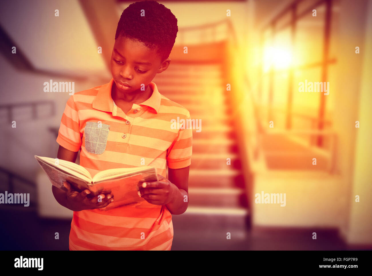 Composite image of cute boy reading book in library Stock Photo - Alamy