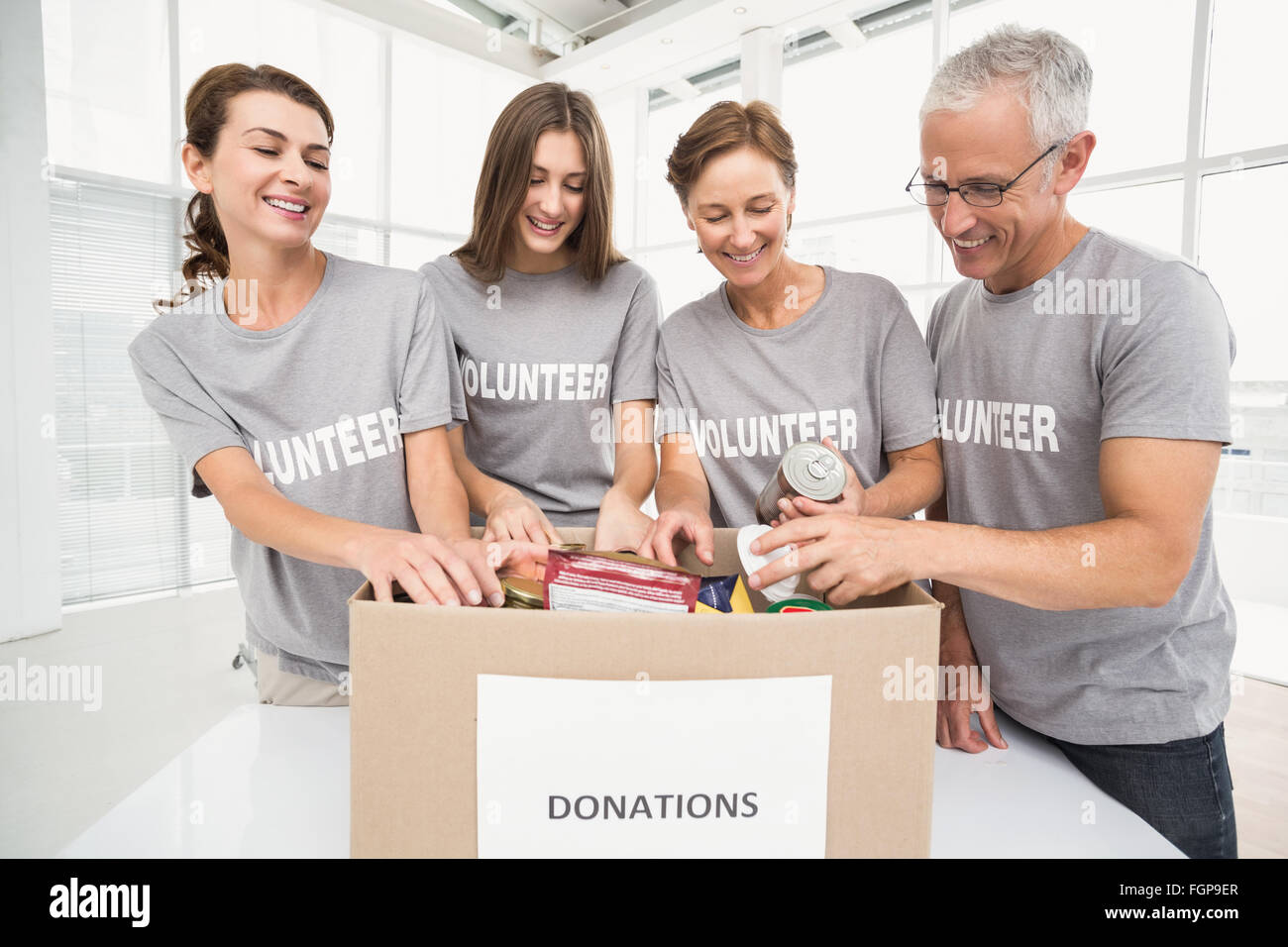 Smiling volunteers sorting donation box Stock Photo - Alamy