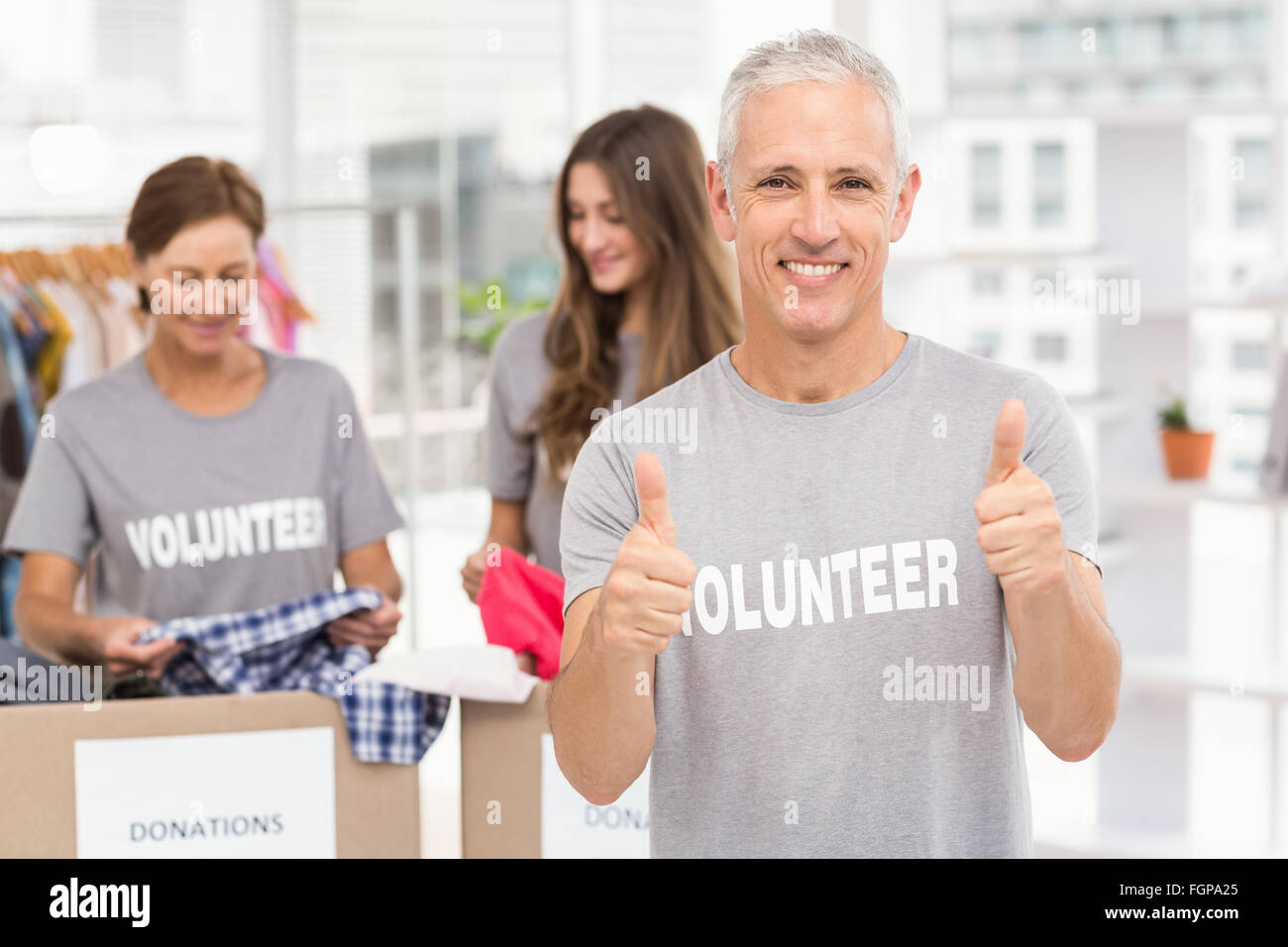 Smiling volunteer doing thumbs up Stock Photo - Alamy