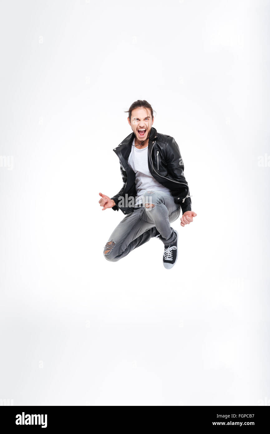 Excited attractive young man screaming and jumping over white ...