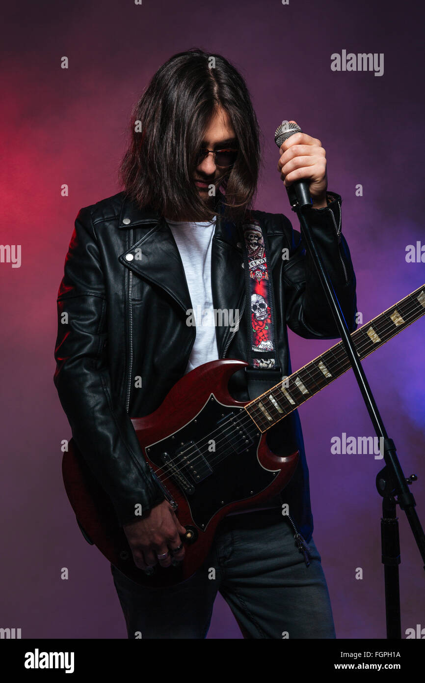 Serious young singer in sunglasses with long hair standing with ...