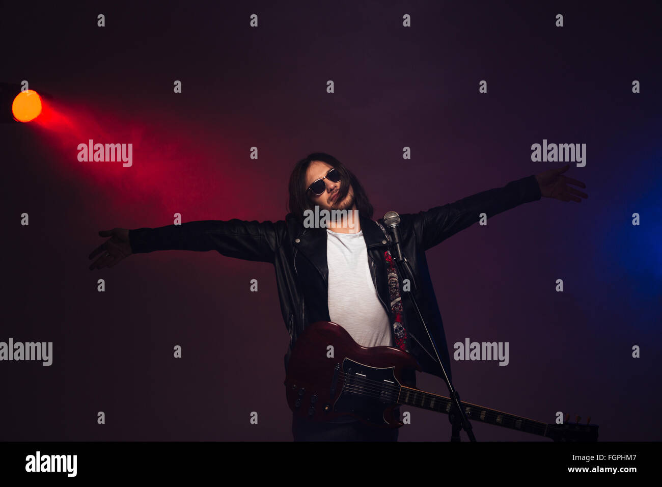 Famous young male singer standing on stage with electric guitar and ...