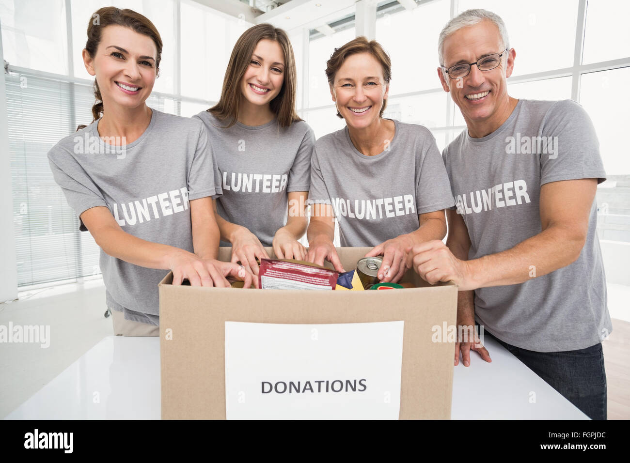 Smiling volunteers sorting donation box Stock Photo - Alamy