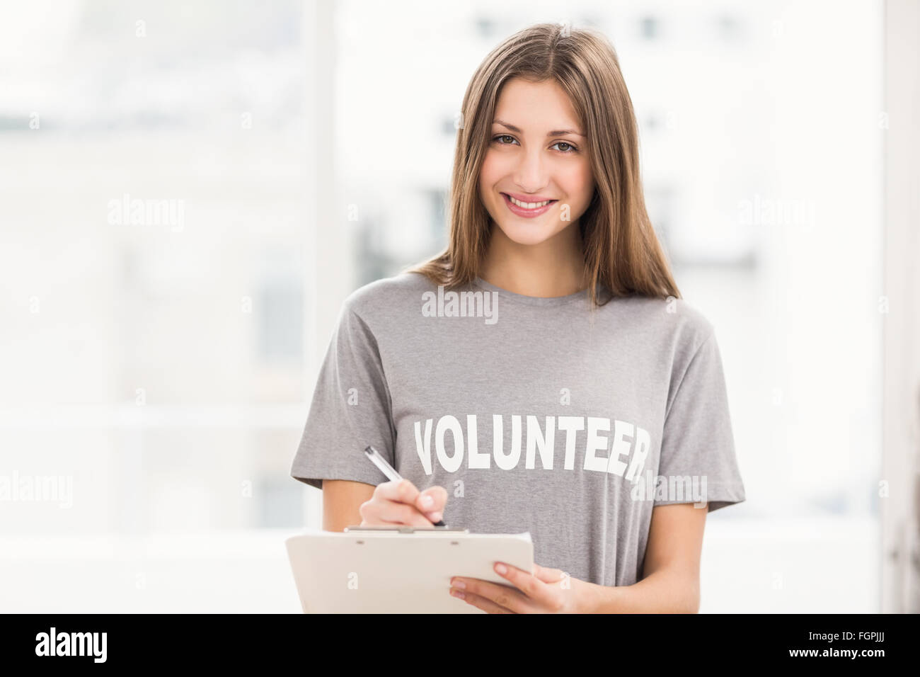 Smiling brunette volunteer with clipboard Stock Photo - Alamy