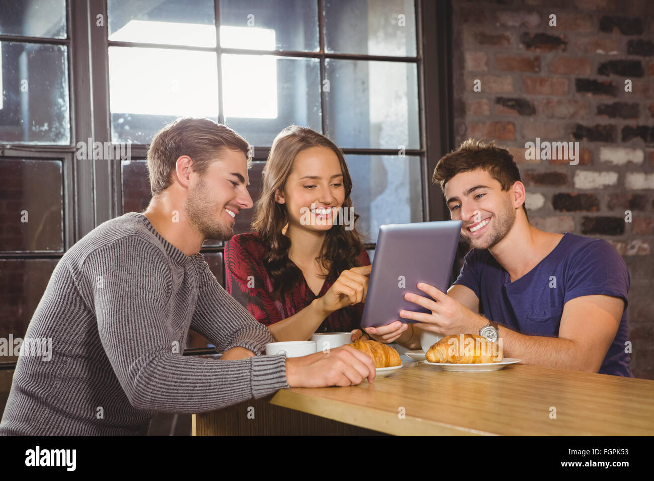 Smiling friends using tablet computer together Stock Photo - Alamy