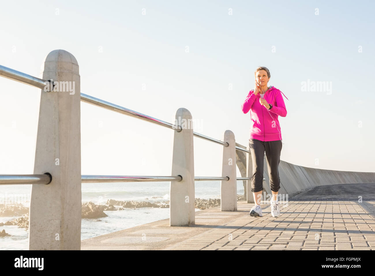 Smiling sporty woman jogging at promenade Stock Photo - Alamy