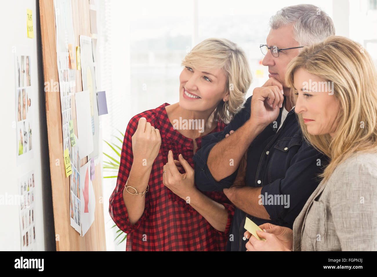 Smiling business team looking at notes on the wall Stock Photo - Alamy