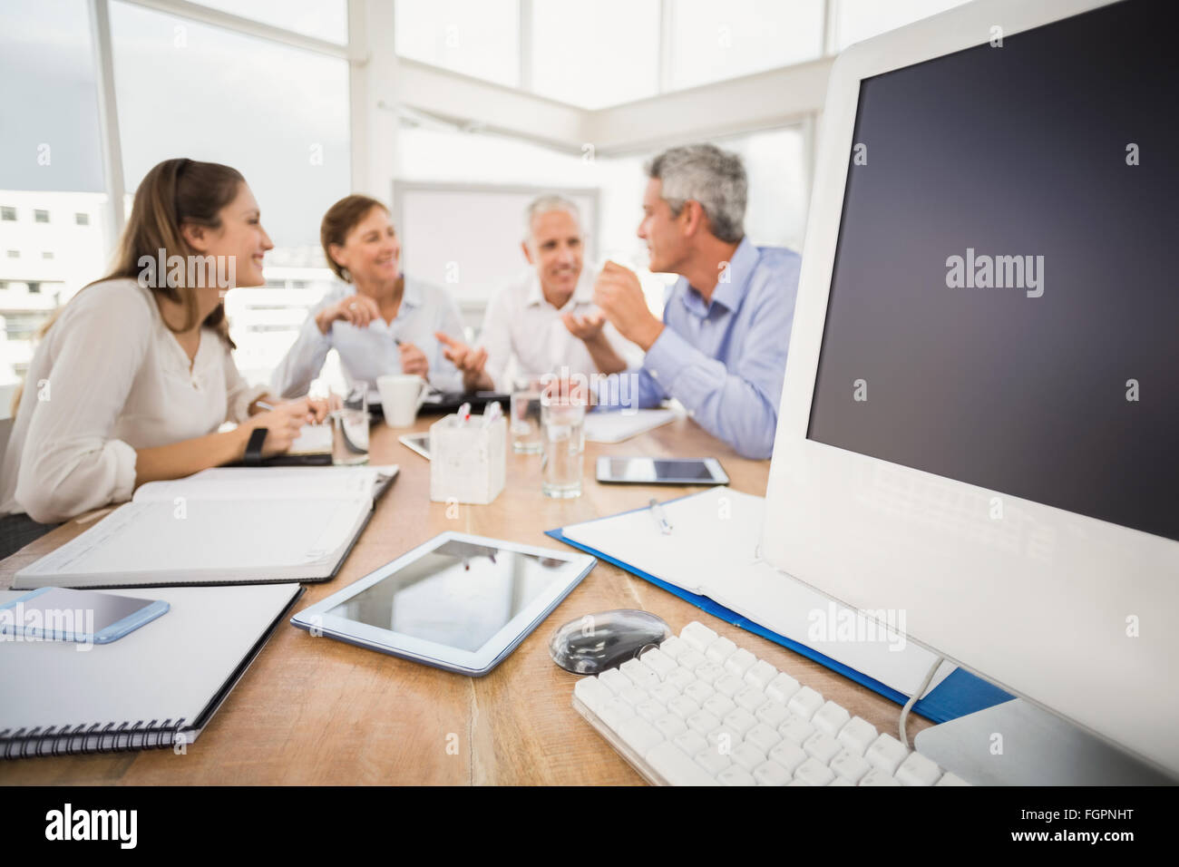 Electronic devices in front of talking business people Stock Photo - Alamy