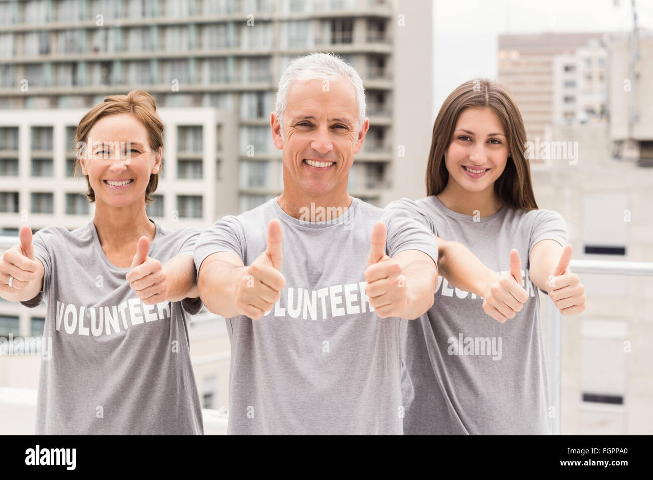 Smiling volunteers doing thumbs up Stock Photo - Alamy
