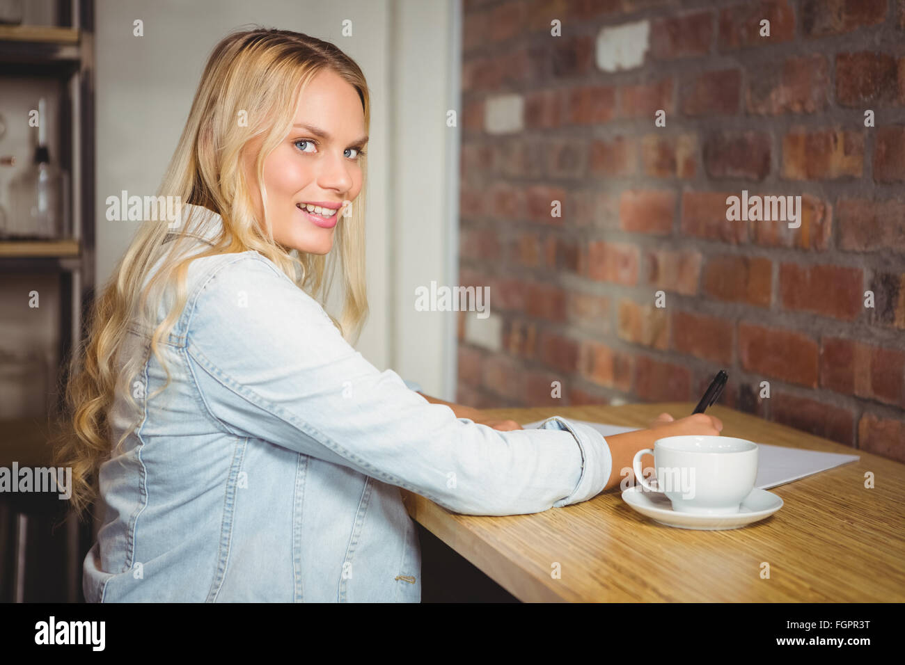 Smiling blonde writing on sheet of paper Stock Photo - Alamy