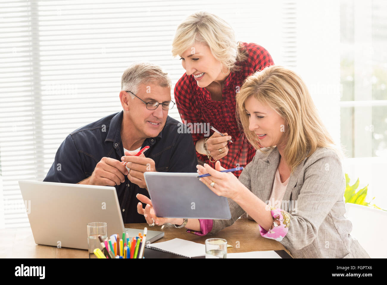 Smiling business team working over a tablet Stock Photo - Alamy