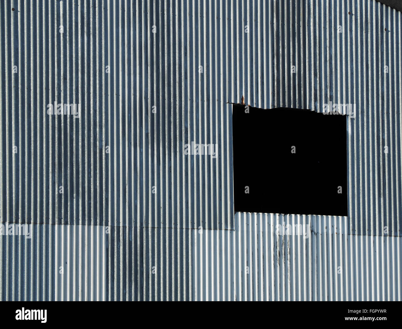 black rectangular hole in wall of corrugated tin sheets of differing ...