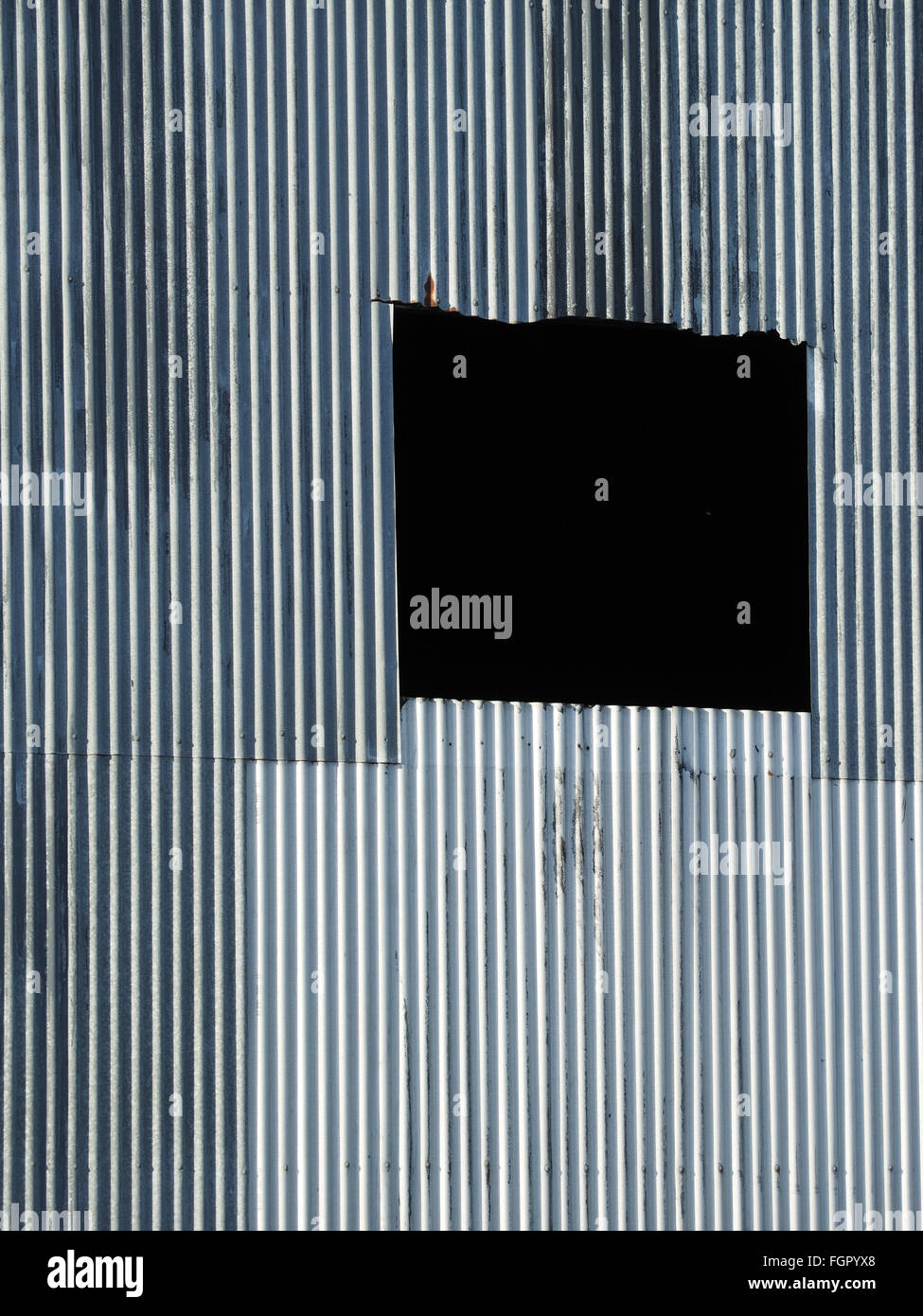 black rectangular hole in wall of corrugated tin sheets of differing ...