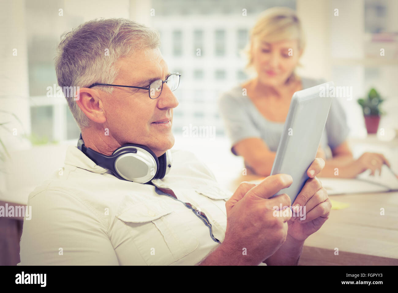 Relaxed businessman looking at his tablet Stock Photo - Alamy