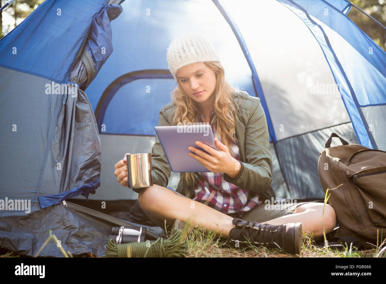 Pretty blonde camper using tablet and holding cup Stock Photo - Alamy