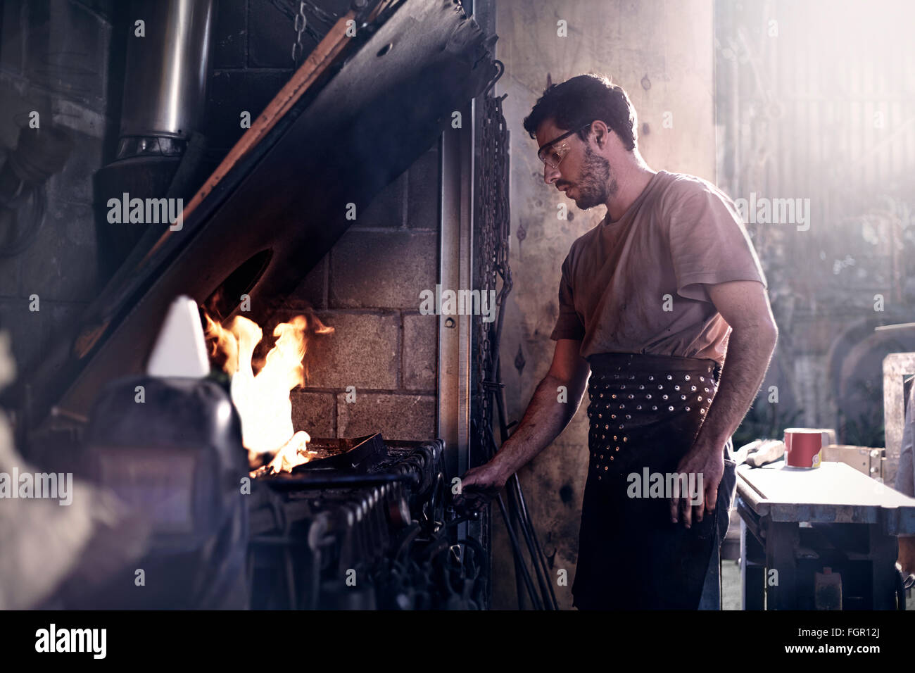 Blacksmith working at fire in forge Stock Photo - Alamy