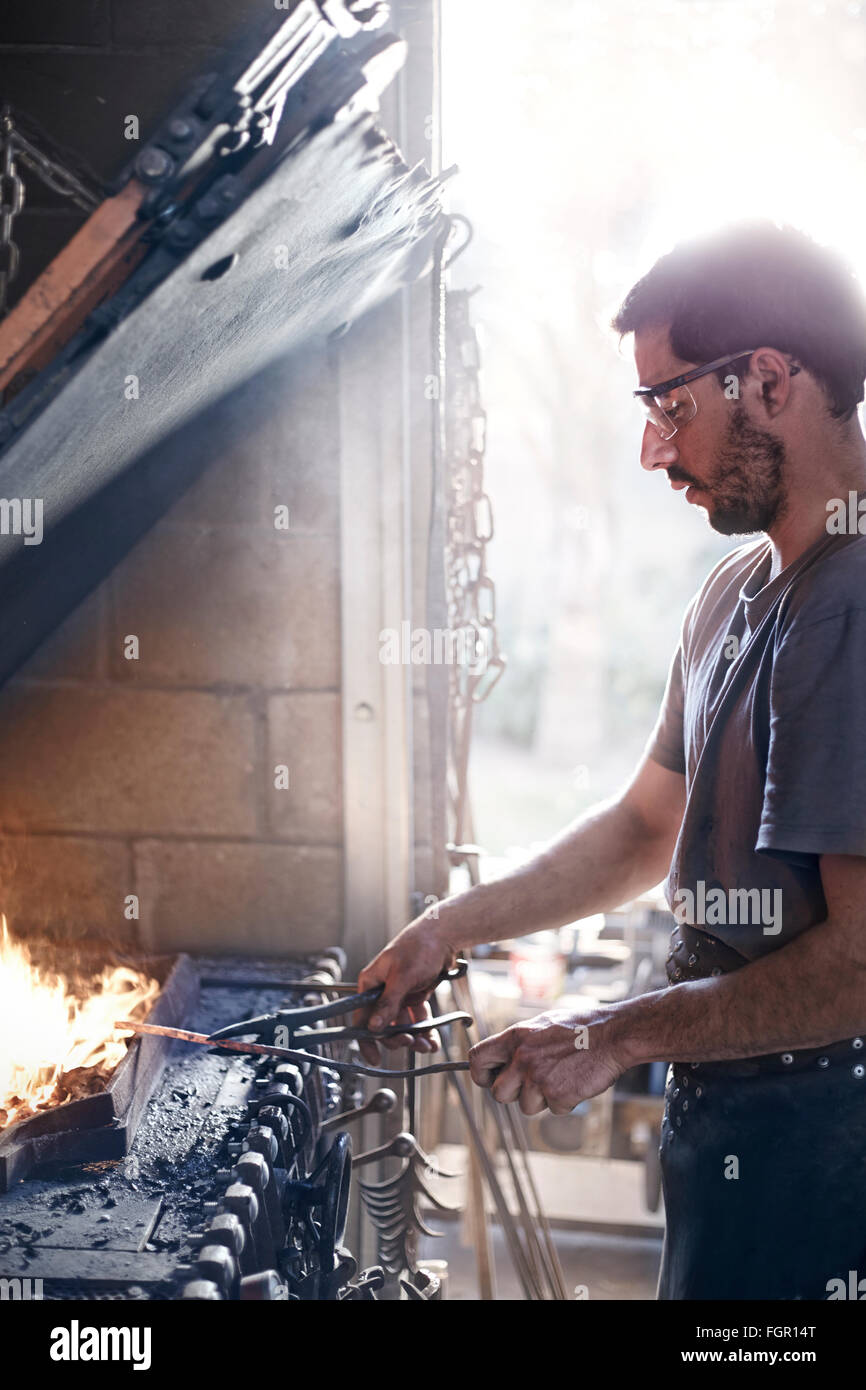 Blacksmith working over fire in forge Stock Photo - Alamy