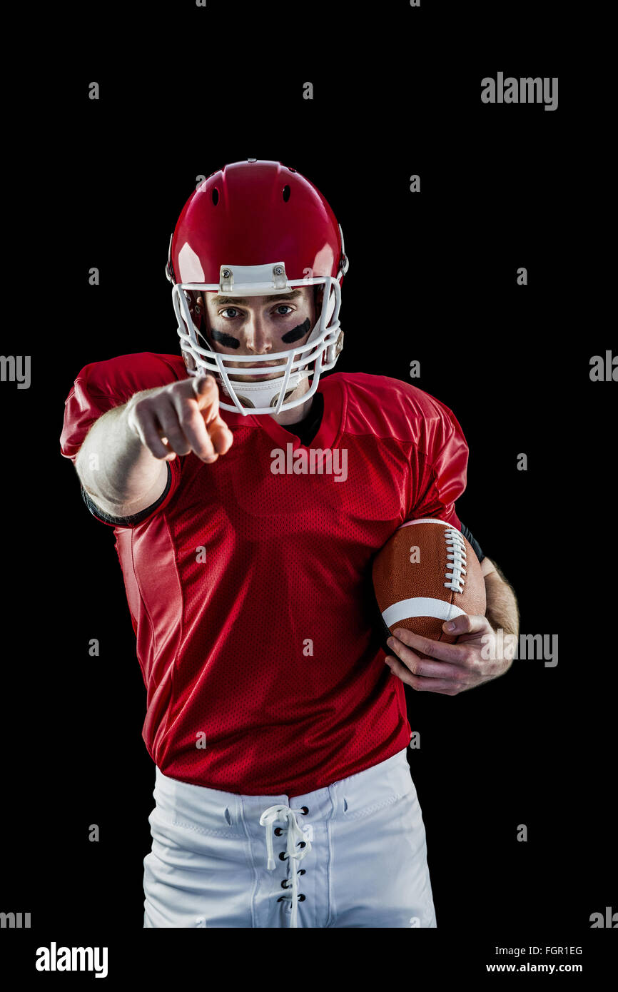 Portrait of american football player holding football and pointing to ...