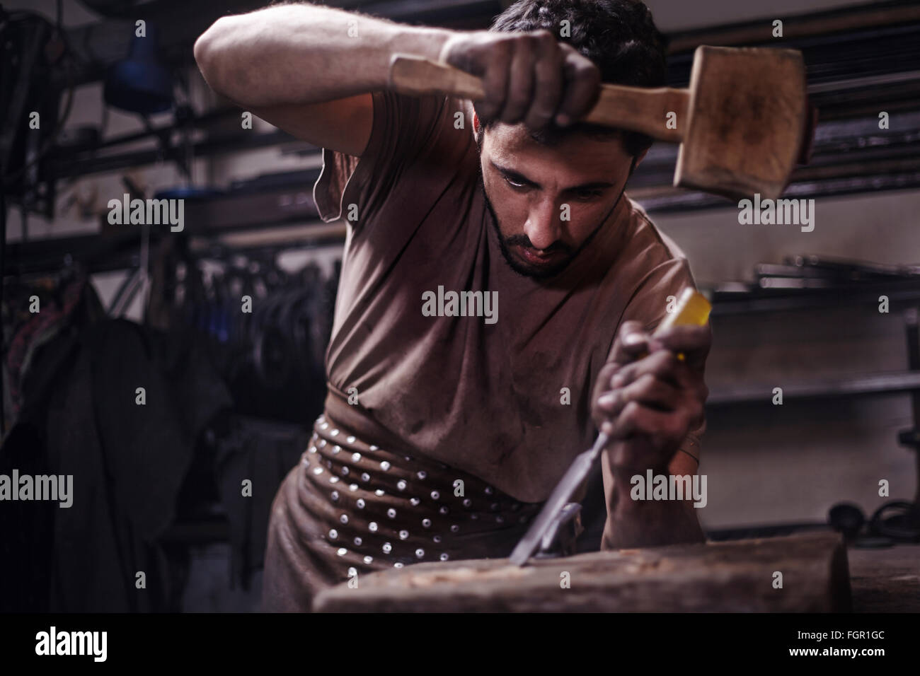 Blacksmith chiseling wood in forge Stock Photo - Alamy