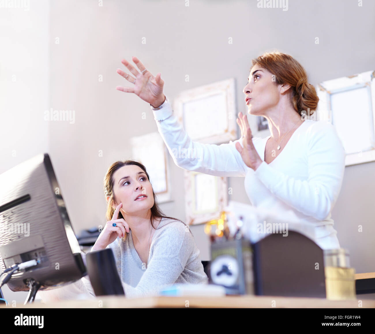 Businesswoman gesturing and explaining to coworker at computer Stock ...