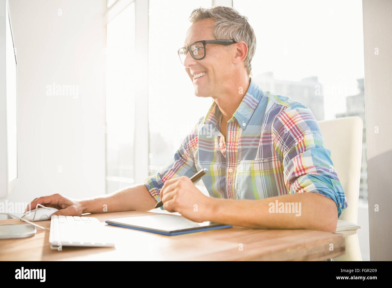 Smiling casual designer using computer and digitizer Stock Photo - Alamy
