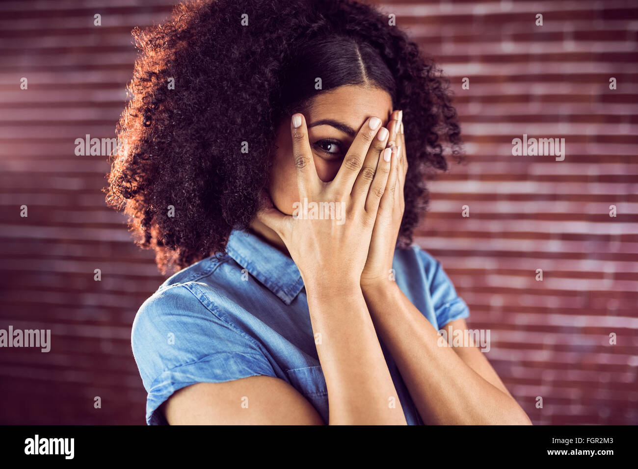 Attractive young woman hiding behind hands Stock Photo - Alamy