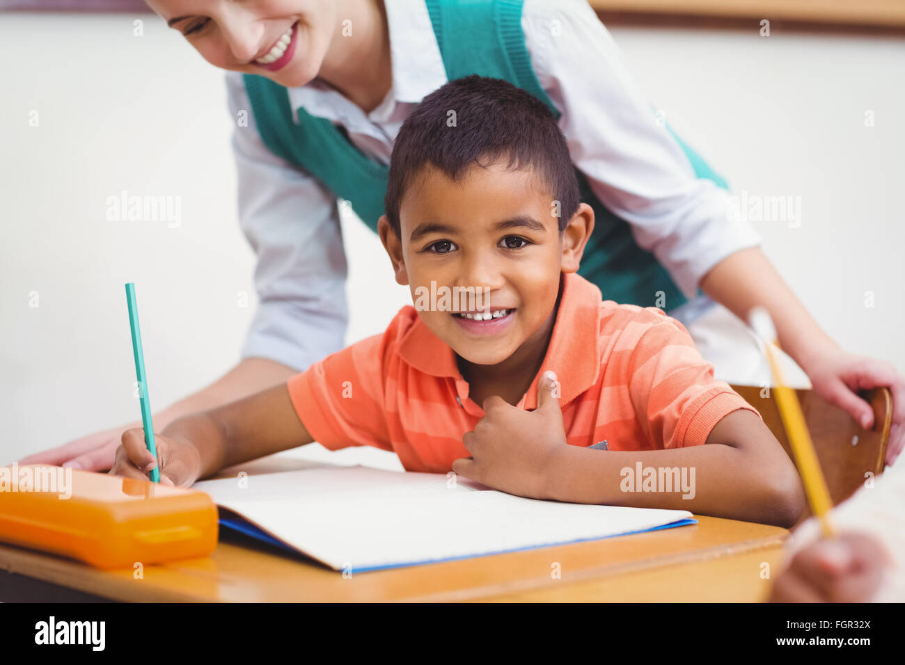 Teacher helping a little boy during class Stock Photo - Alamy