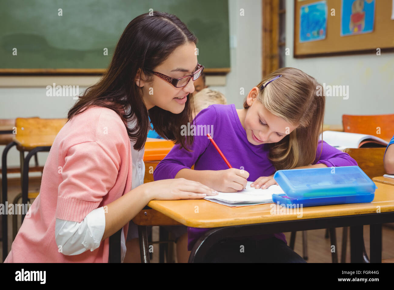 Happy teacher helping her students Stock Photo - Alamy