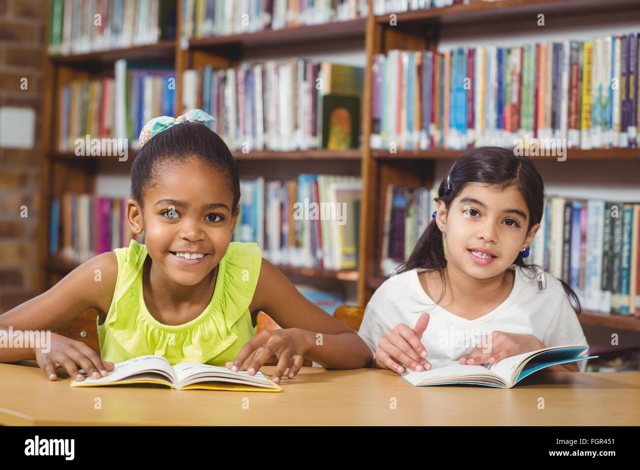 Smiling pupils reading books in the library Stock Photo - Alamy