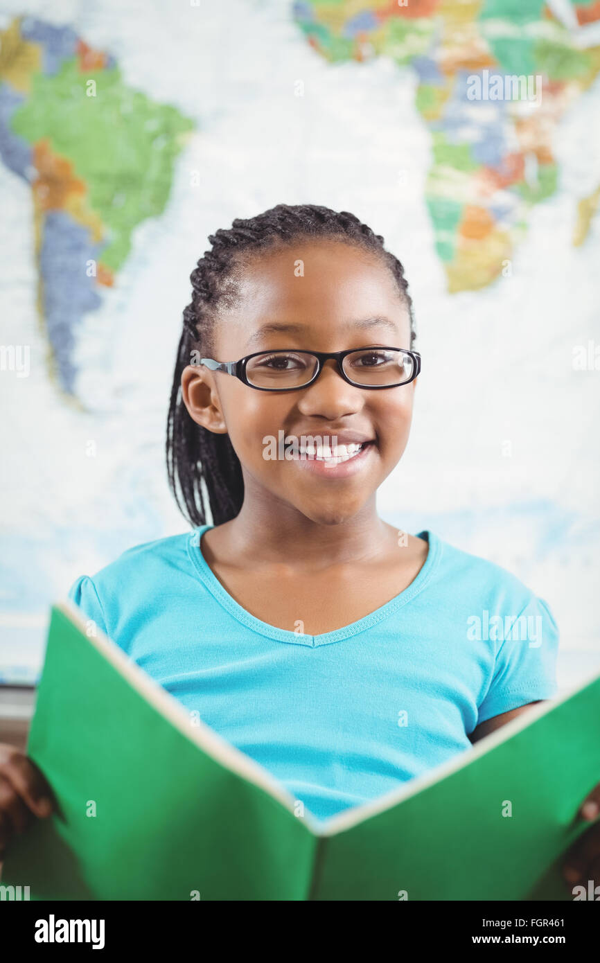 Smiling pupil reading book in a classroom Stock Photo - Alamy