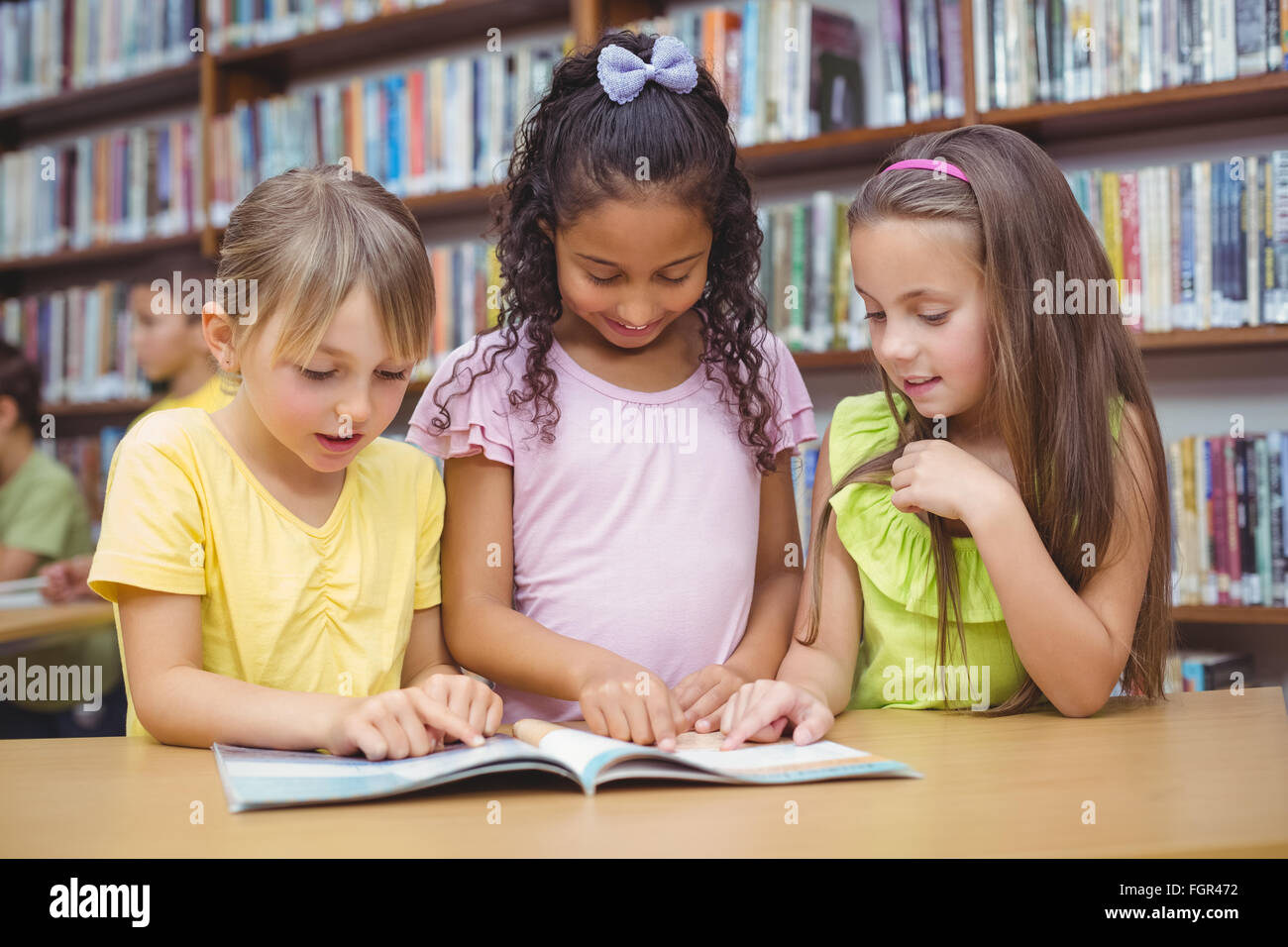 Pupils reading book together in library Stock Photo - Alamy