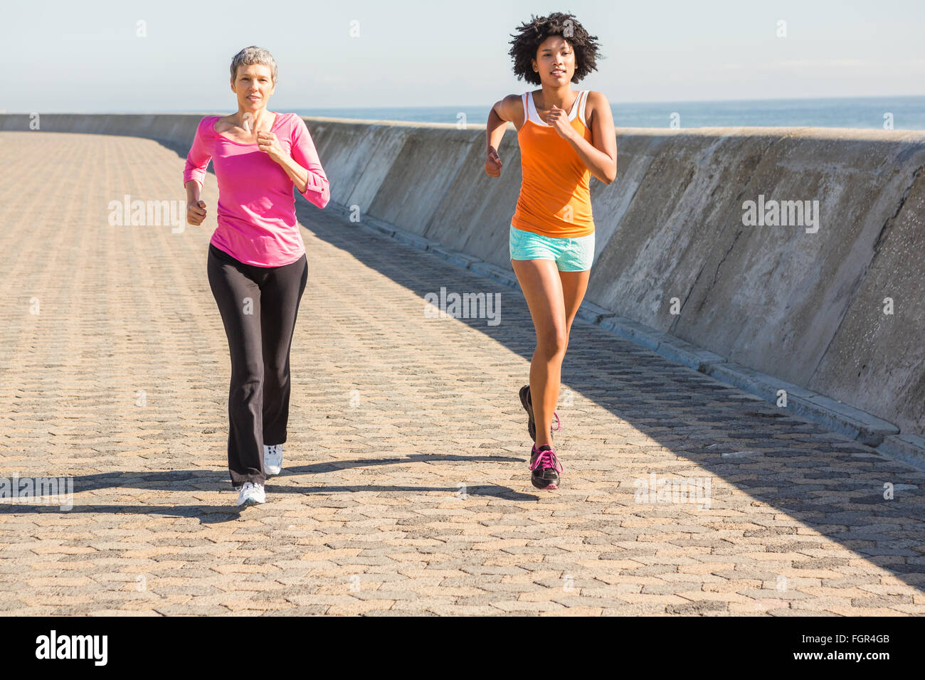 Two sporty women jogging together Stock Photo - Alamy