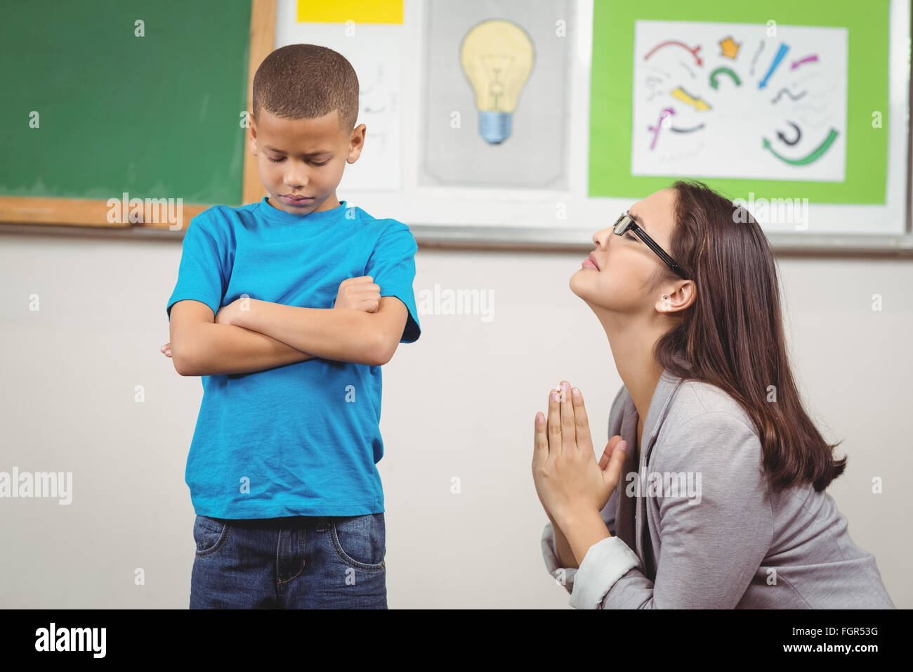Pretty teacher begging pupil for something Stock Photo - Alamy
