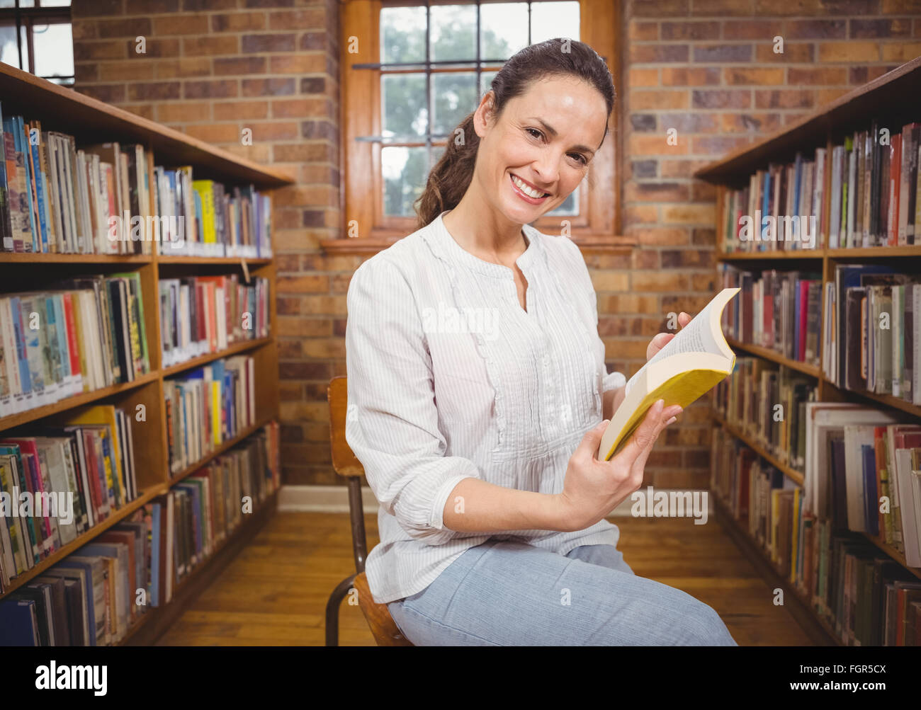 Smiling teacher reading a book Stock Photo - Alamy